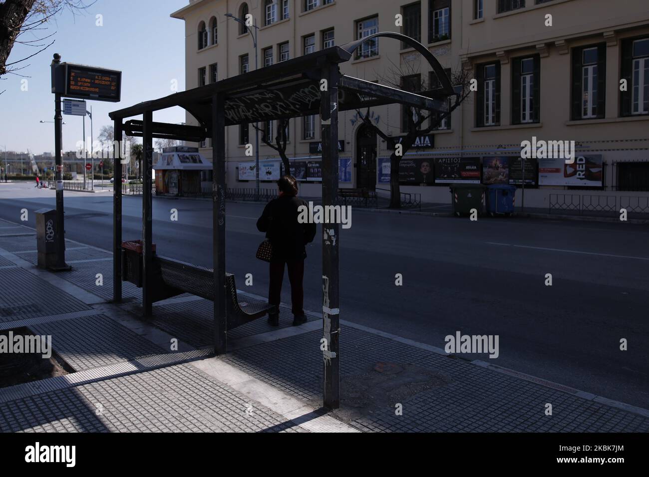 A woman is seen waiting in an empty bus stop, in Thessaloniki, in ...