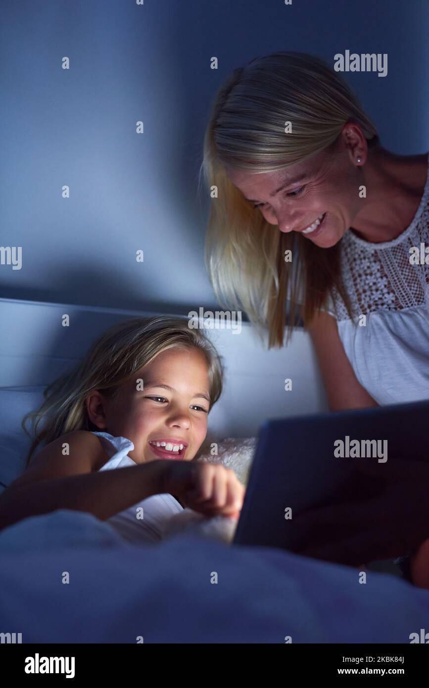 She loves funny cartoons. a little girl and her mother using a digital ...