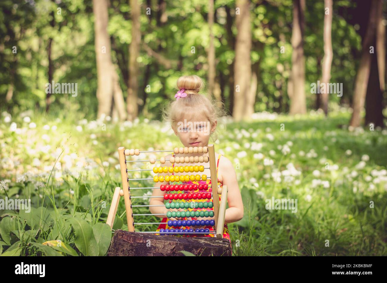 cute little girl sitting in the spring green forest and counting in abacus Stock Photo - Alamy