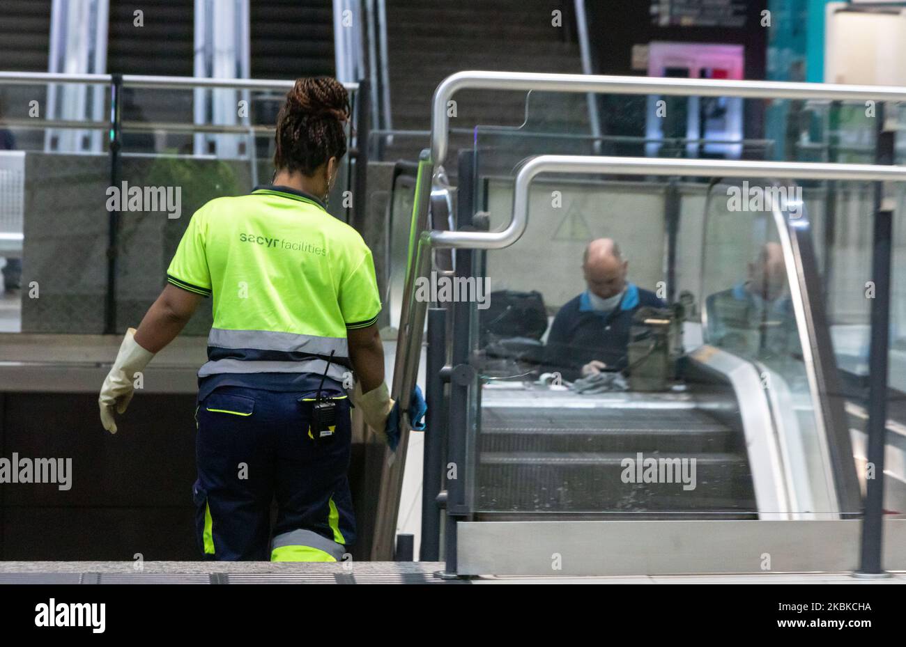 A woman disinfects a railing at Moncloa station while a man repairs the ...
