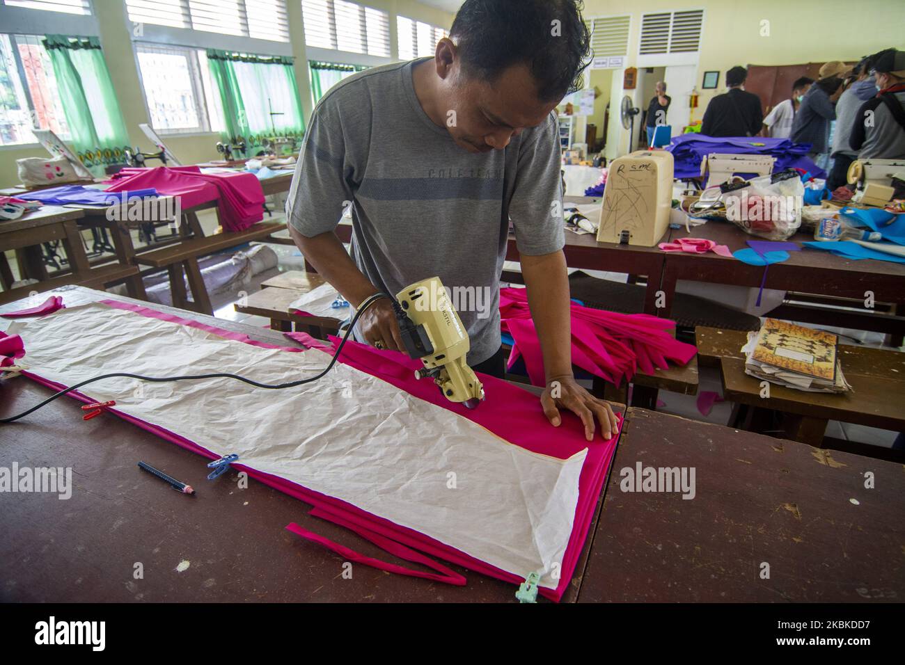 A teacher cuts cloth to make personal protective clothing at a high ...