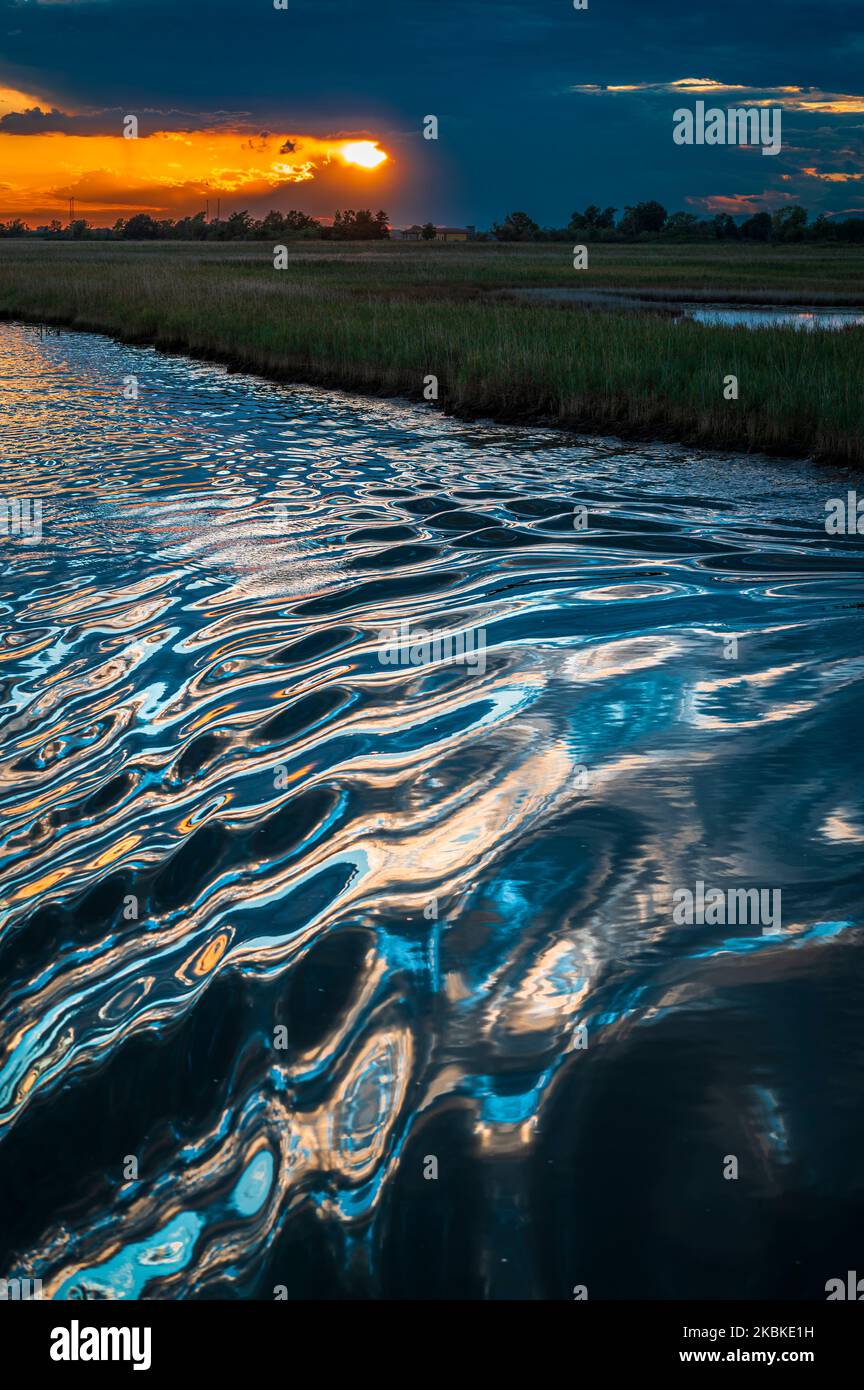 Towards the sunset. Marano lagoon late summer colors. Clouds and sun ...