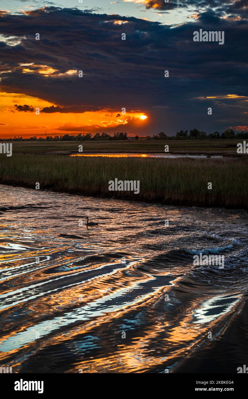 Towards the sunset. Marano lagoon late summer colors. Clouds and sun ...