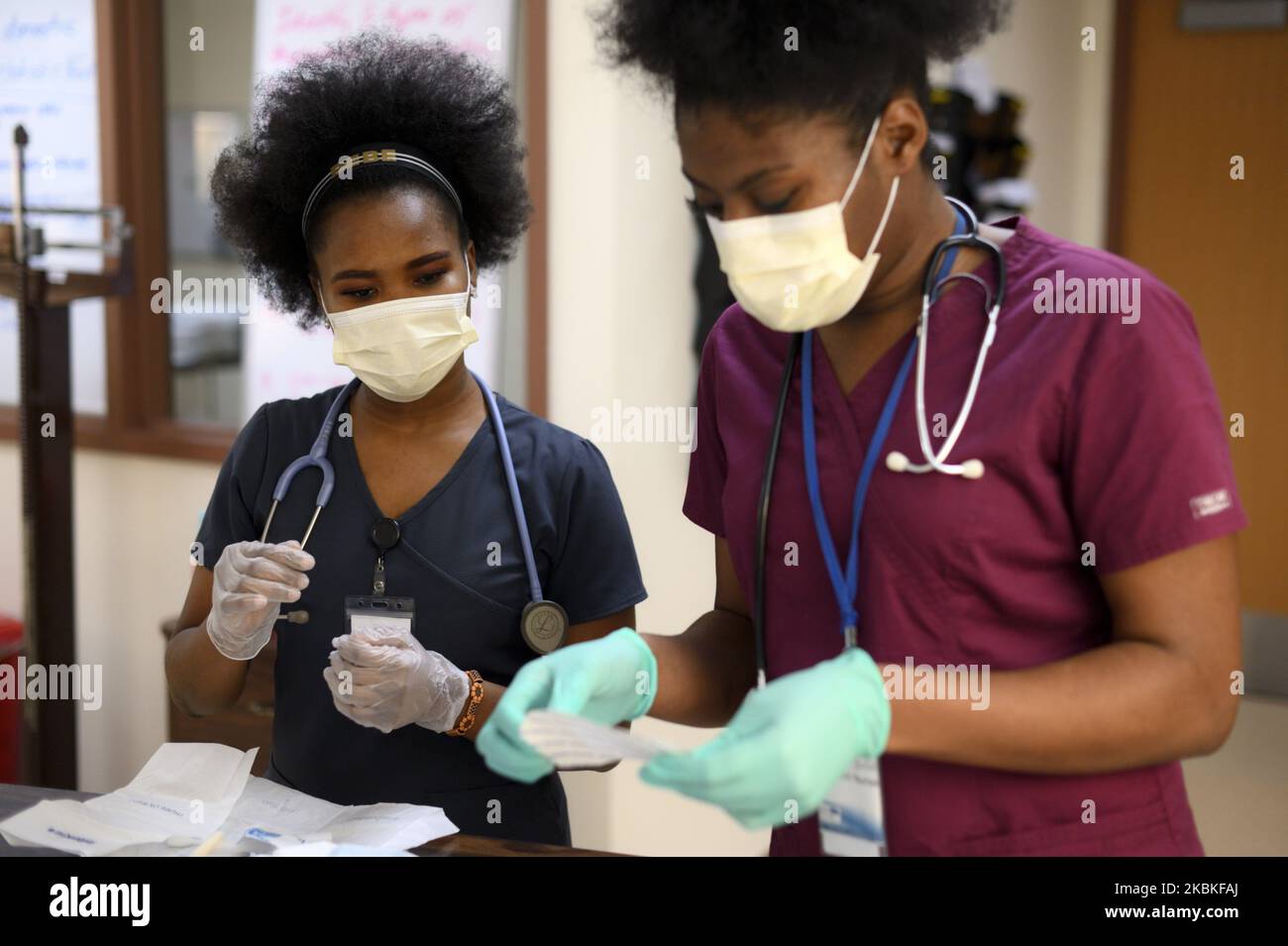 Student nurses Nazarine Beweh and Nicole Obisie attend to a patient ...