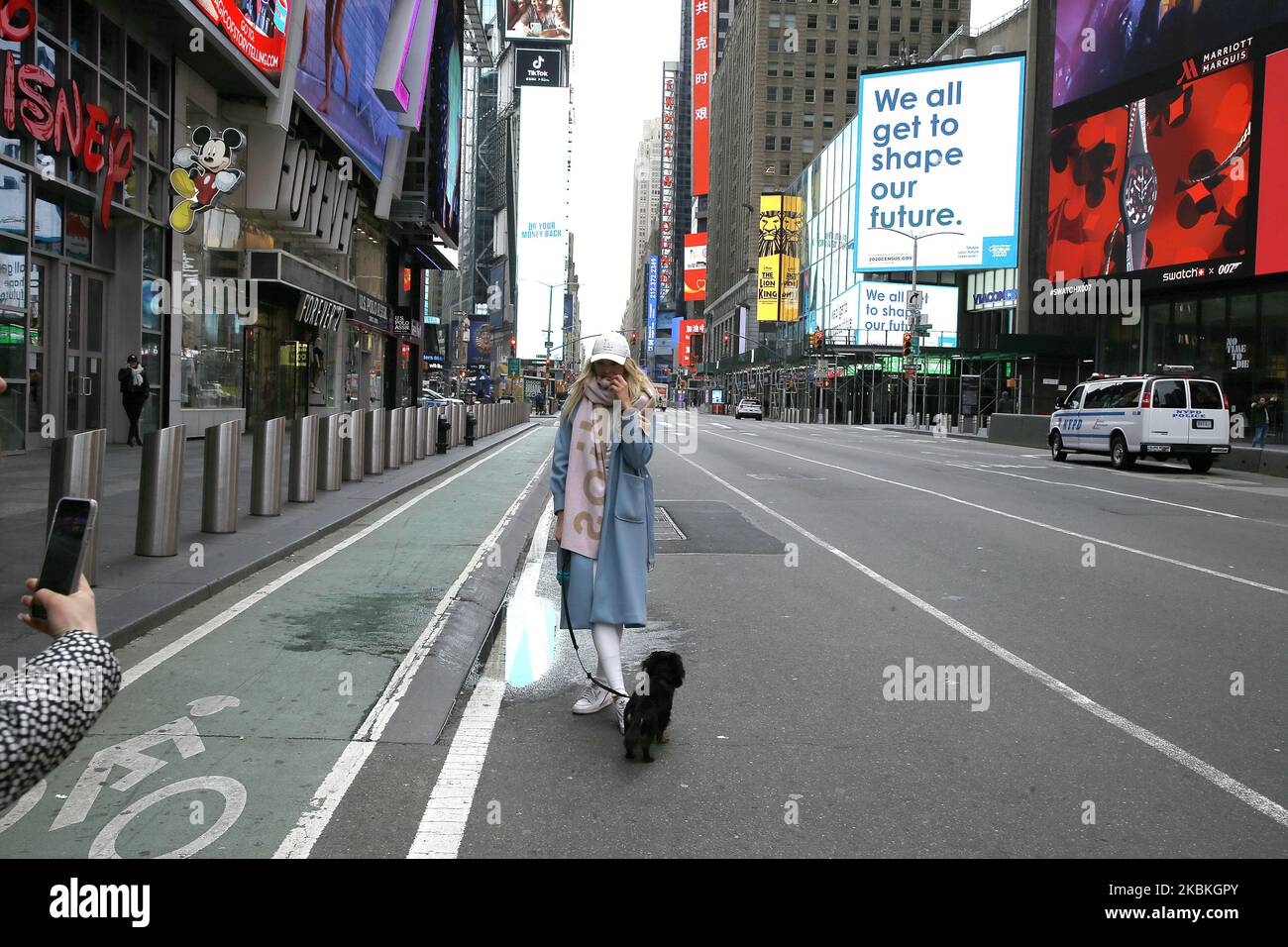 A woman poses as her friend snaps a photo in a mostly empty Times ...