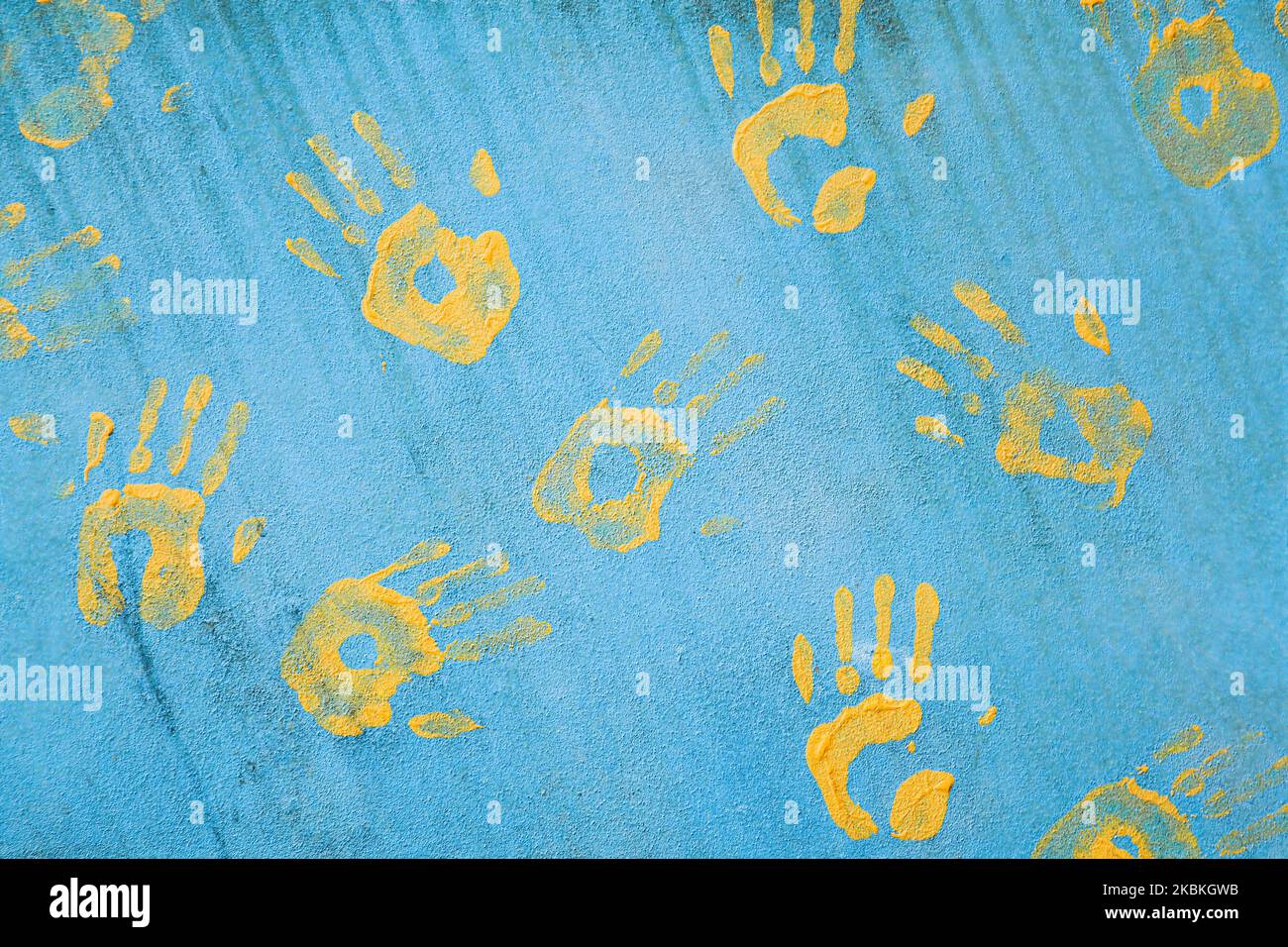 Handprints on the wall. Yellow prints on a blue wall. The background of ...