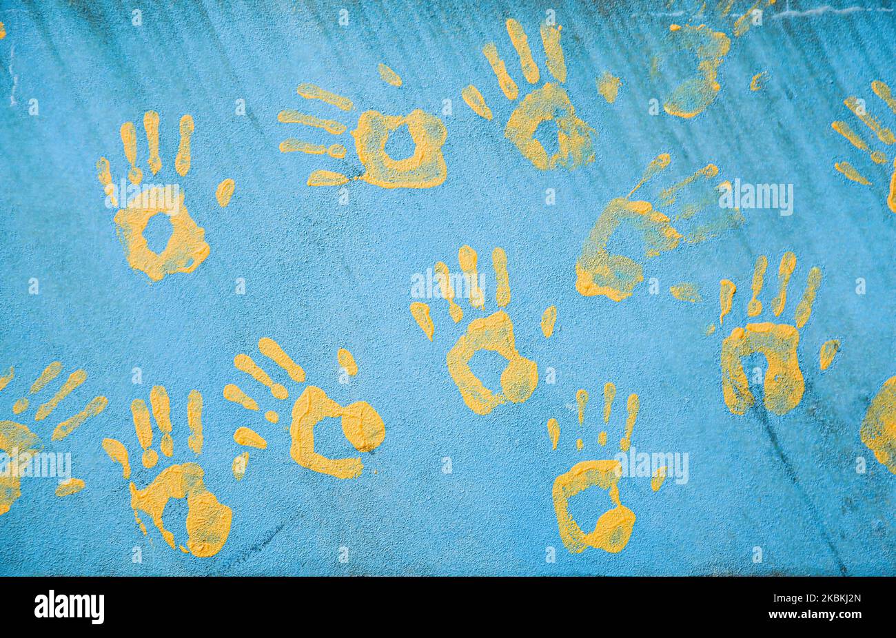 Handprints on the wall. Yellow prints on a blue wall. The background of ...