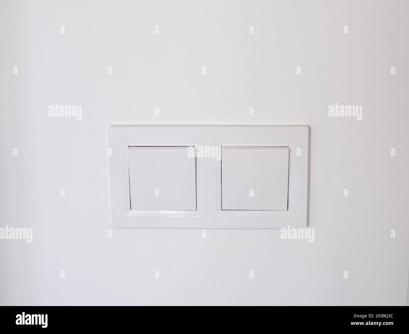 Double white plastic mechanical switches, installed on a white wall ...