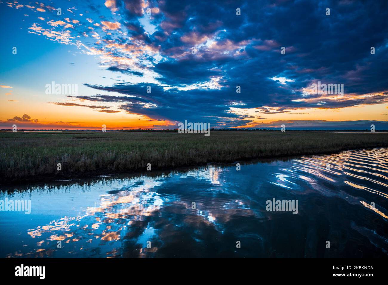 Towards the sunset. Marano lagoon late summer colors. Clouds and sun ...