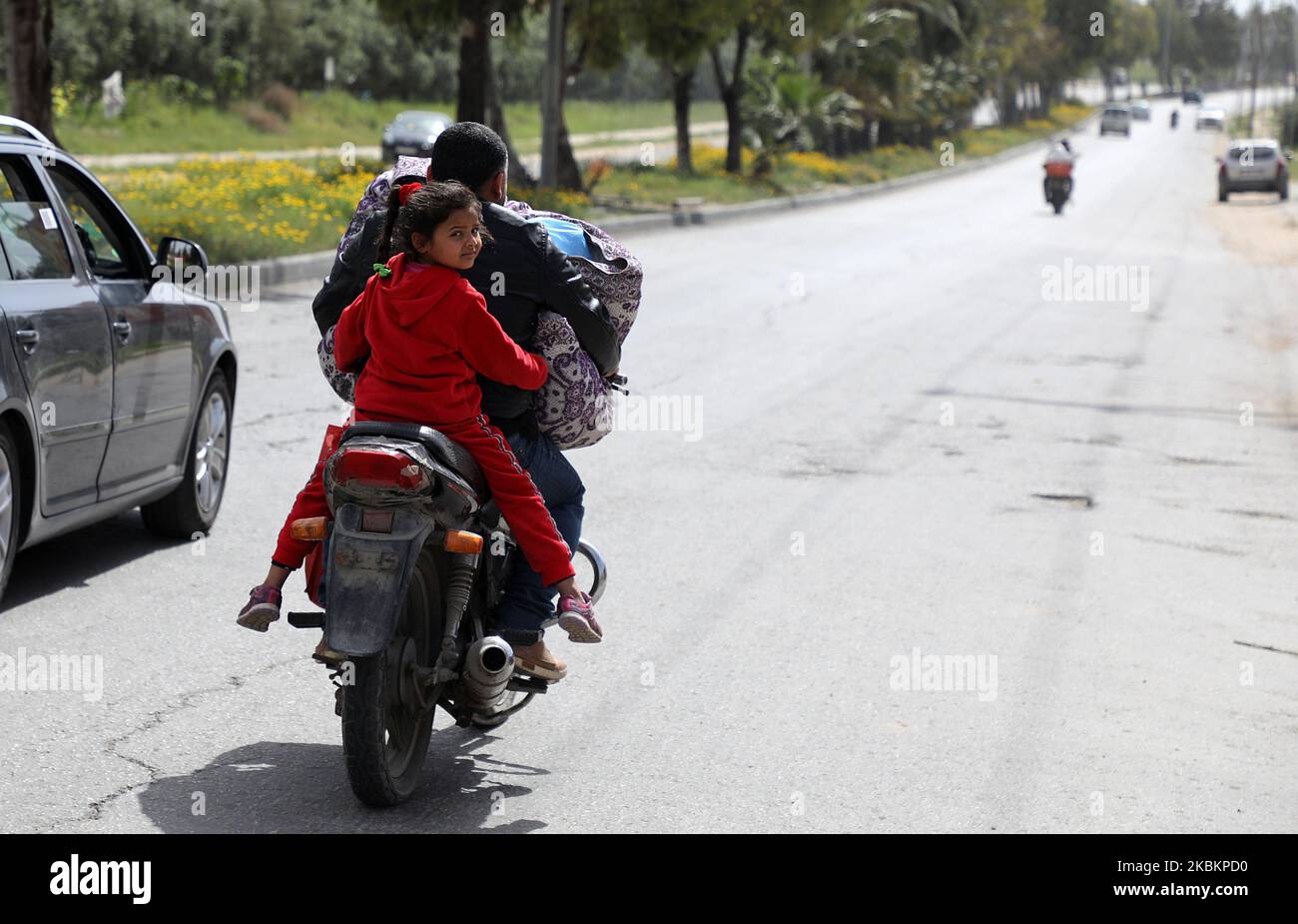 A Palestinian girl rides a motorcycle with her father in the street of ...