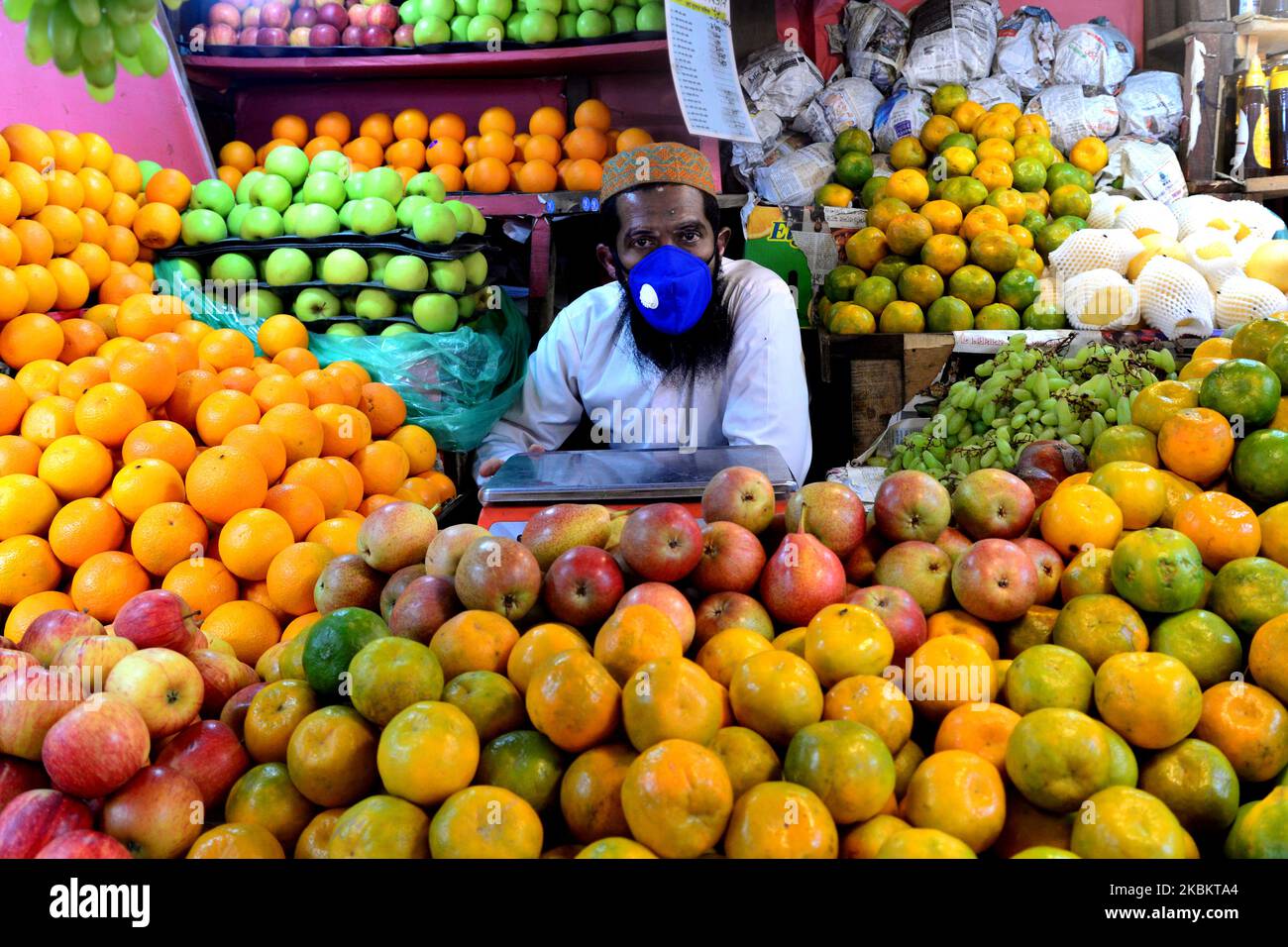 A Bangladeshi fruit vendor waits for customer at a kitchen market during a government-imposed ...