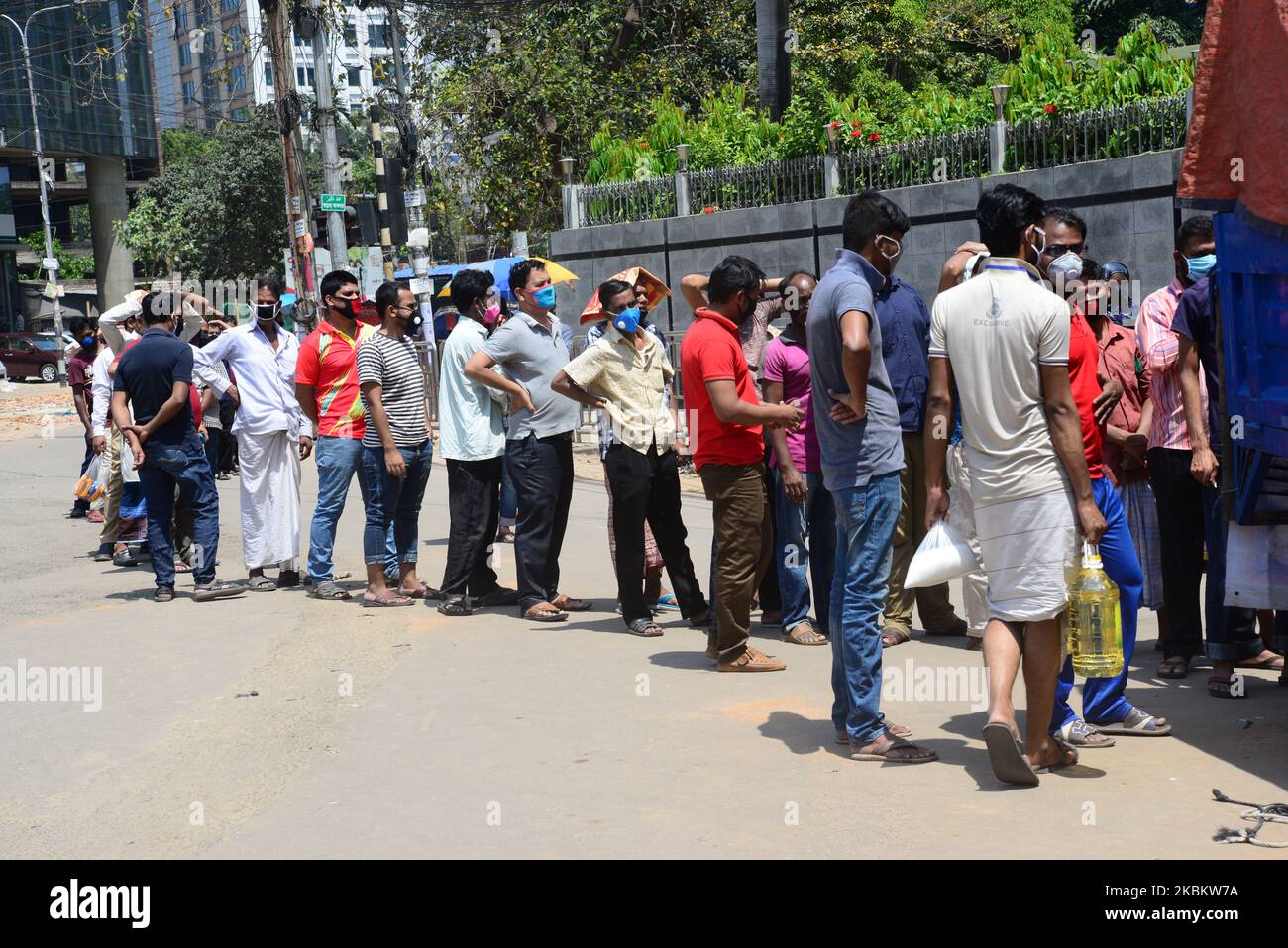 Bangladeshi people in a queue to collect goods from a truck of Trading Corporation of Bangladesh ...