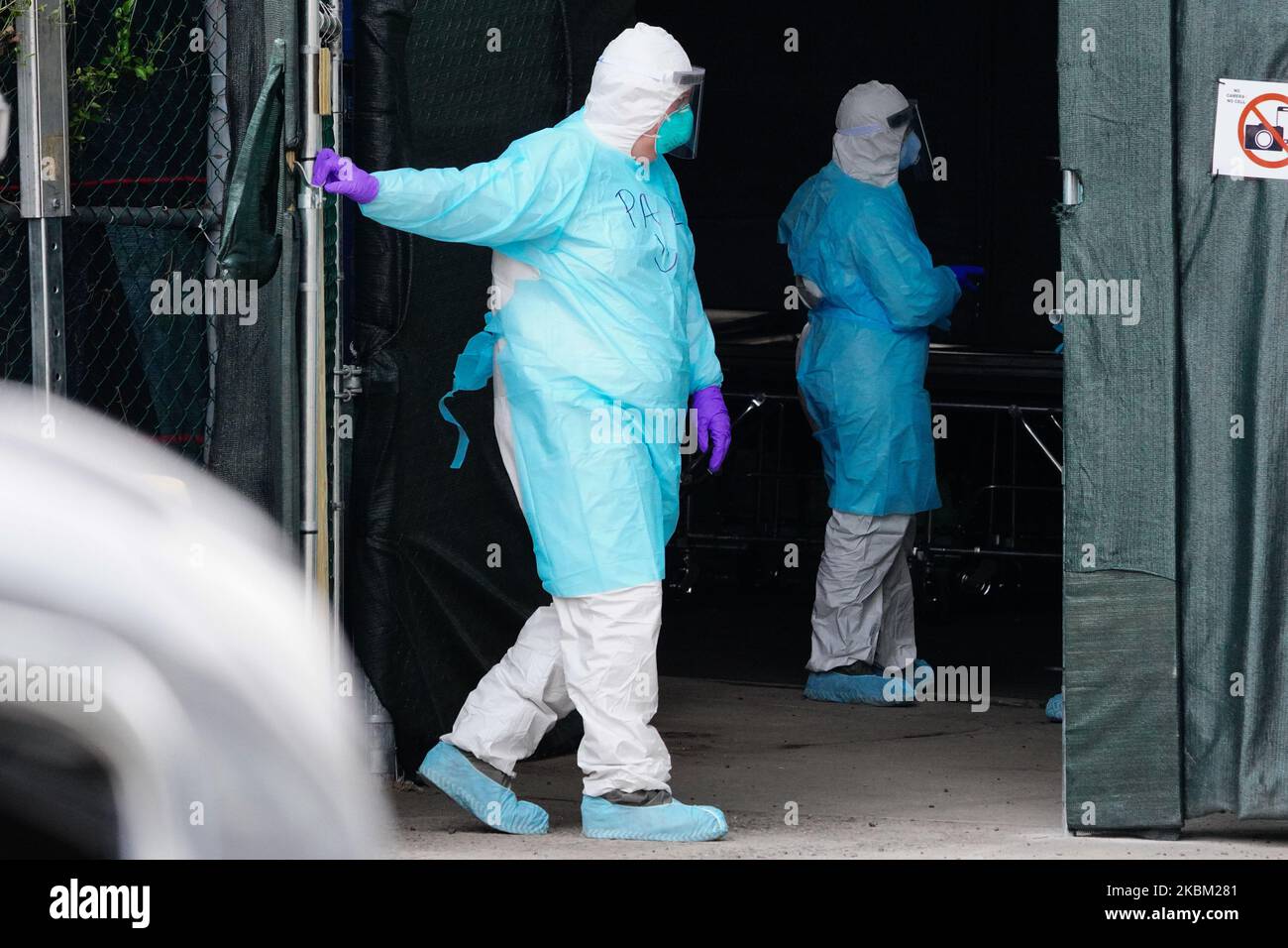 Medical examiner personnel are seen in a makeshift morgue behind ...