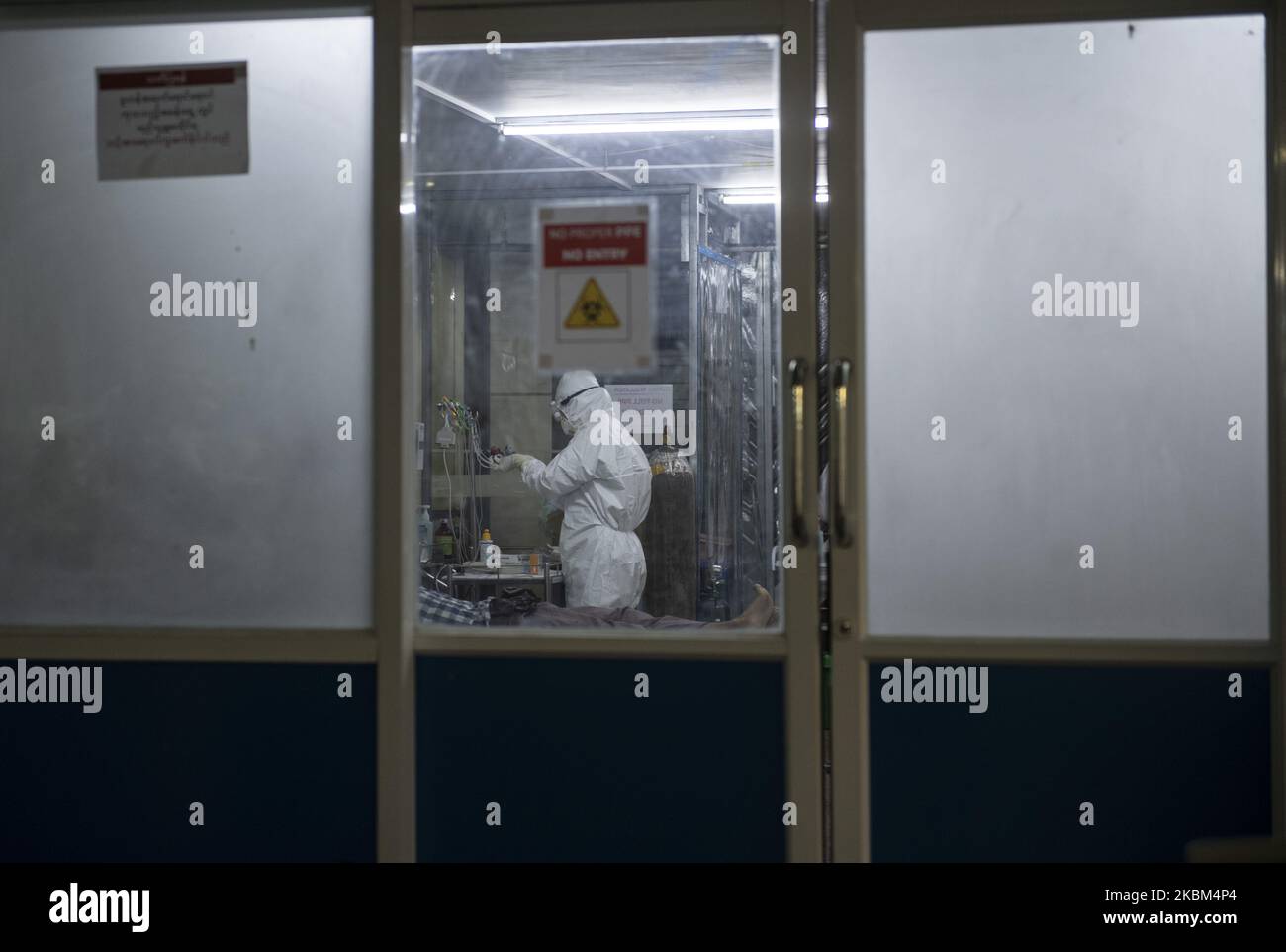 A medical worker in protective suit treats a supected patient inside an ...