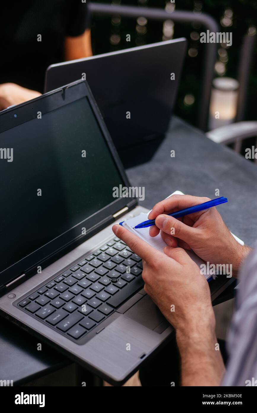 A close up photo of businessman writing some notes down. Working online ...