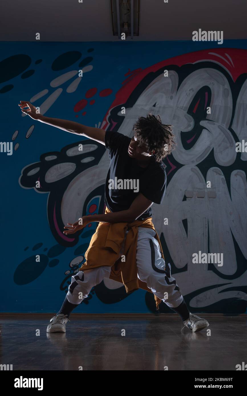 African American hip hop dancer (breakdancer) performing over graffiti ...
