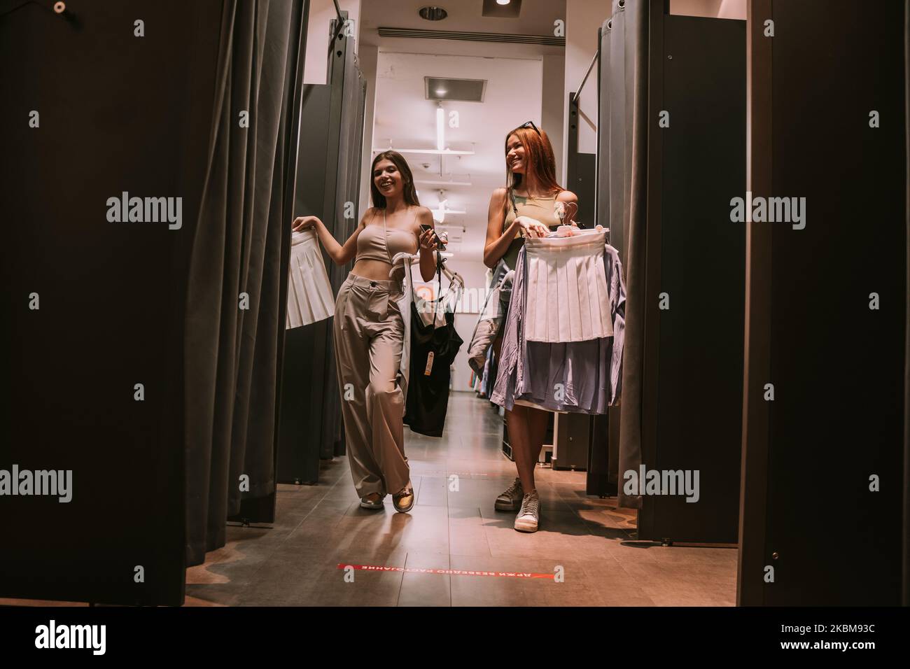 Two teenage pretty girls standing at the changeing room in the shop ...