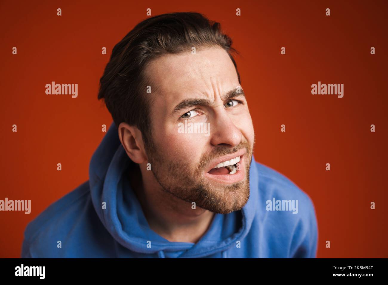 Young perplexity man frowning and looking at camera isolated over red ...