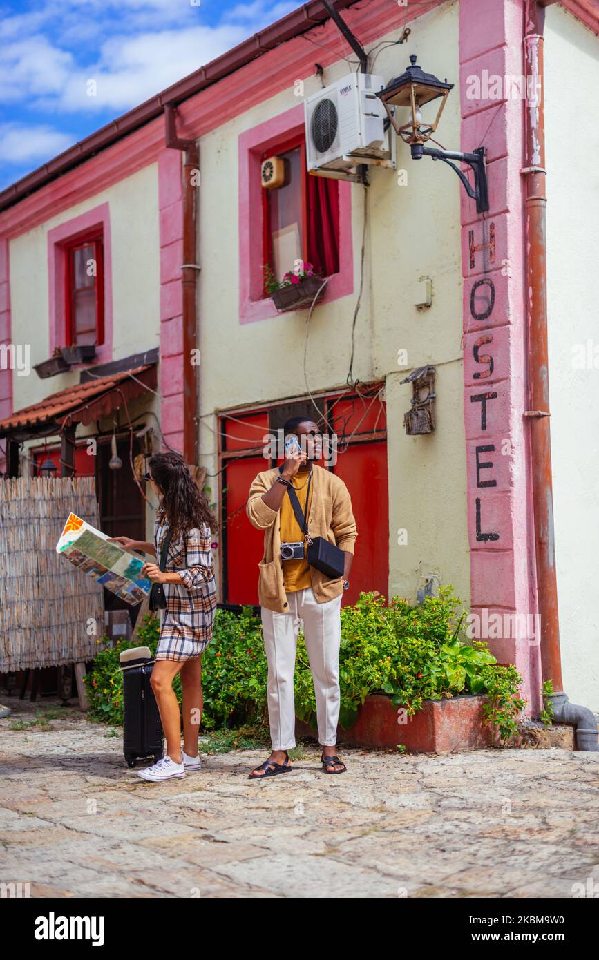 A very handsome black male is calling a taxi while his caucasian ...