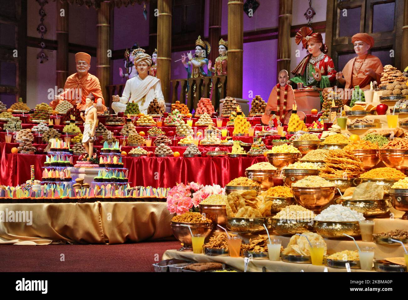 Mountains of sweets and vegetarian snacks are displayed in front of the ...