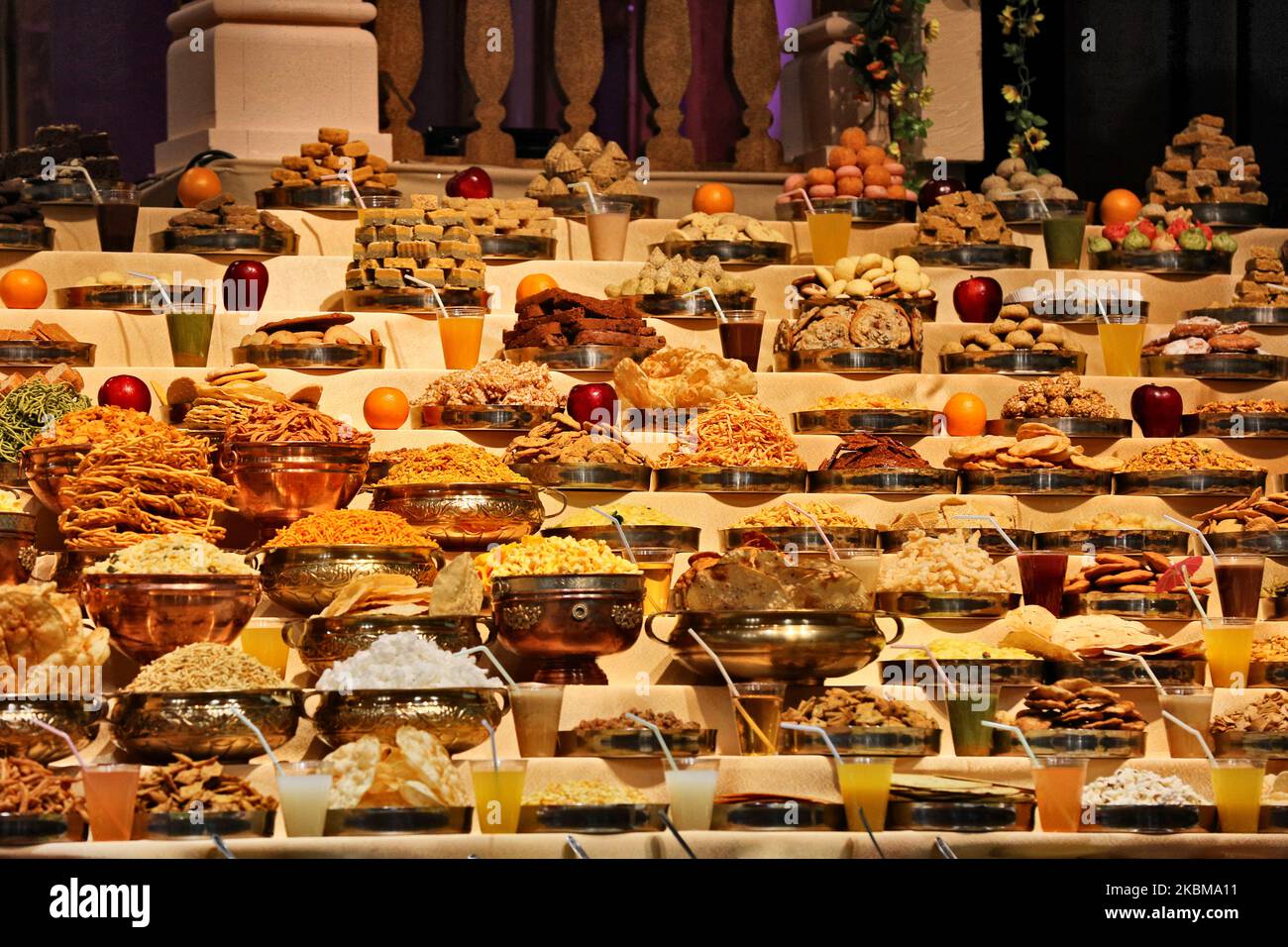 Mountains of sweets and vegetarian snacks are displayed in front of the ...