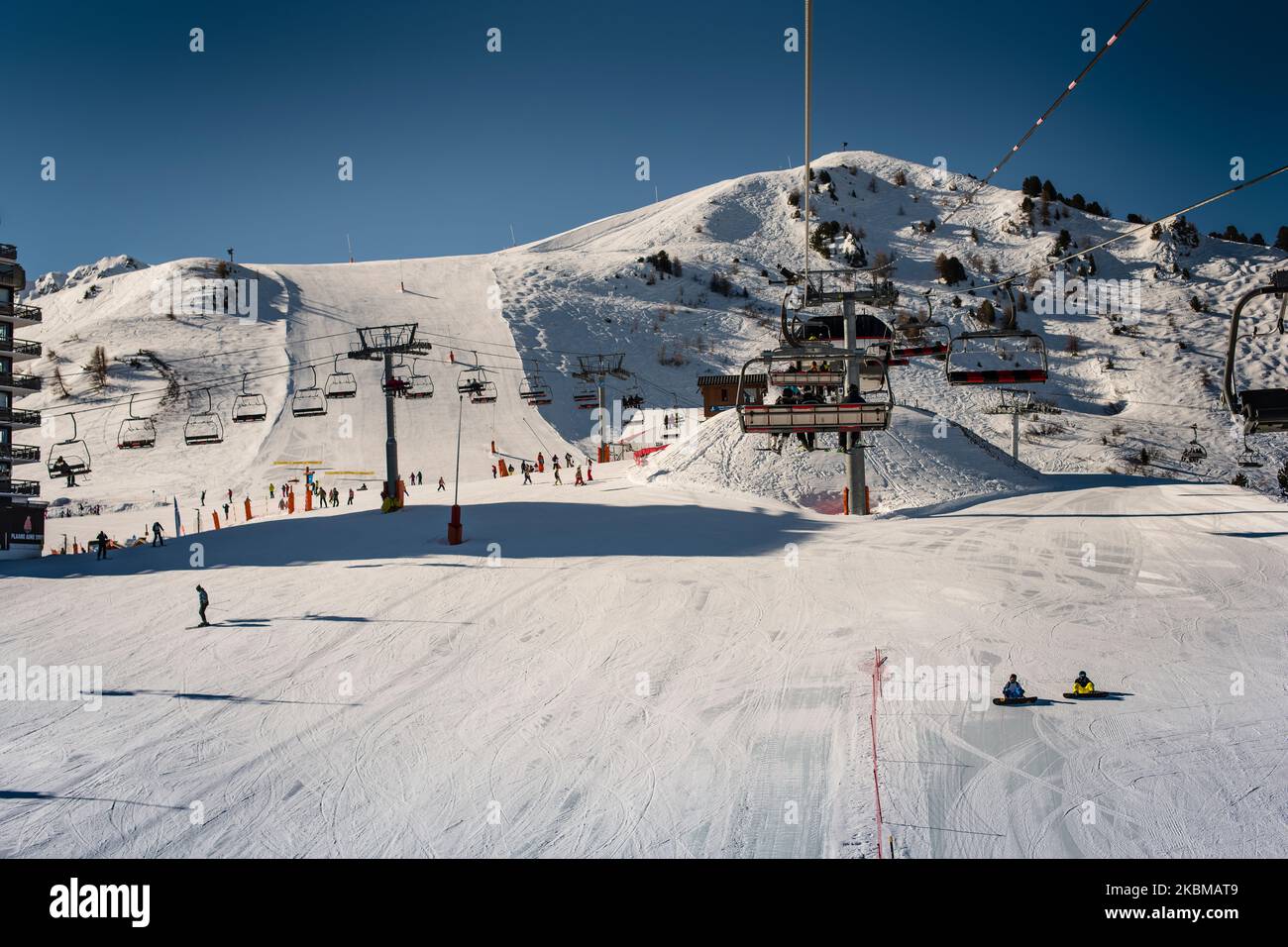 Skiers and chairlifts in ski village and skiers on the piste ski runs ...
