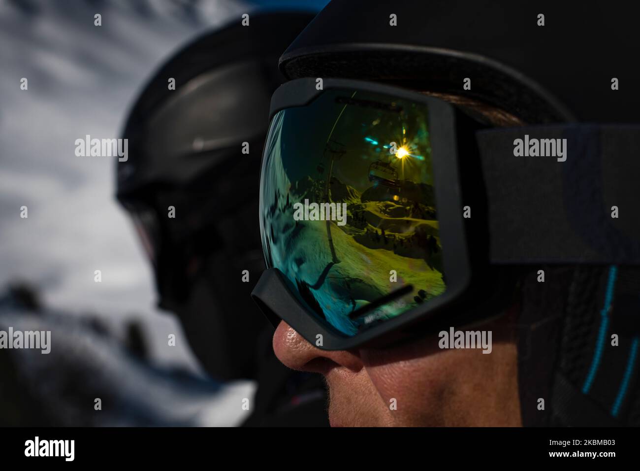 Two skiers on chairlift helmets and goggles on lady on the lift ...