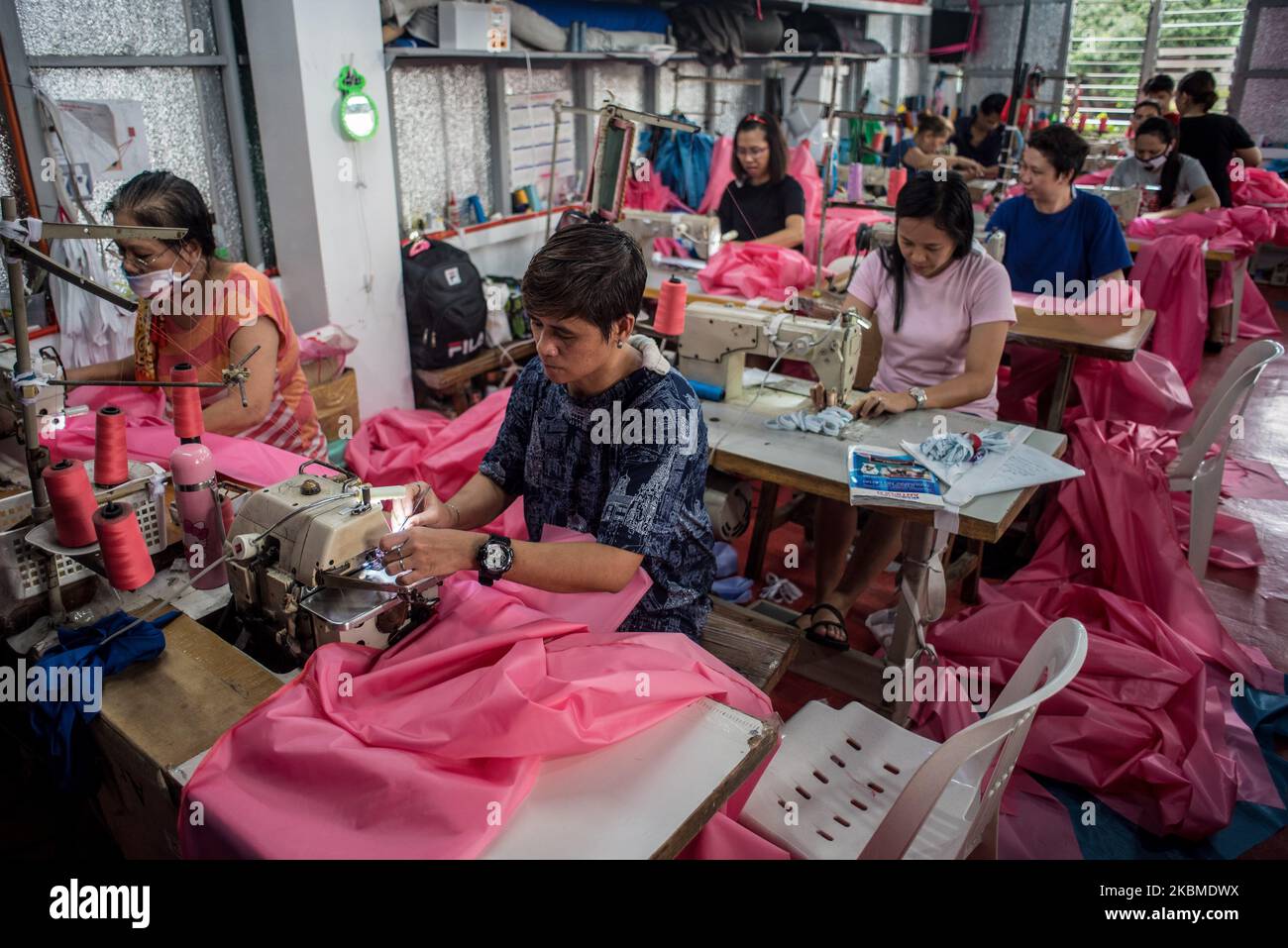 Seamstresses sew protective equipment (PPE) suits in a tailor shop in ...