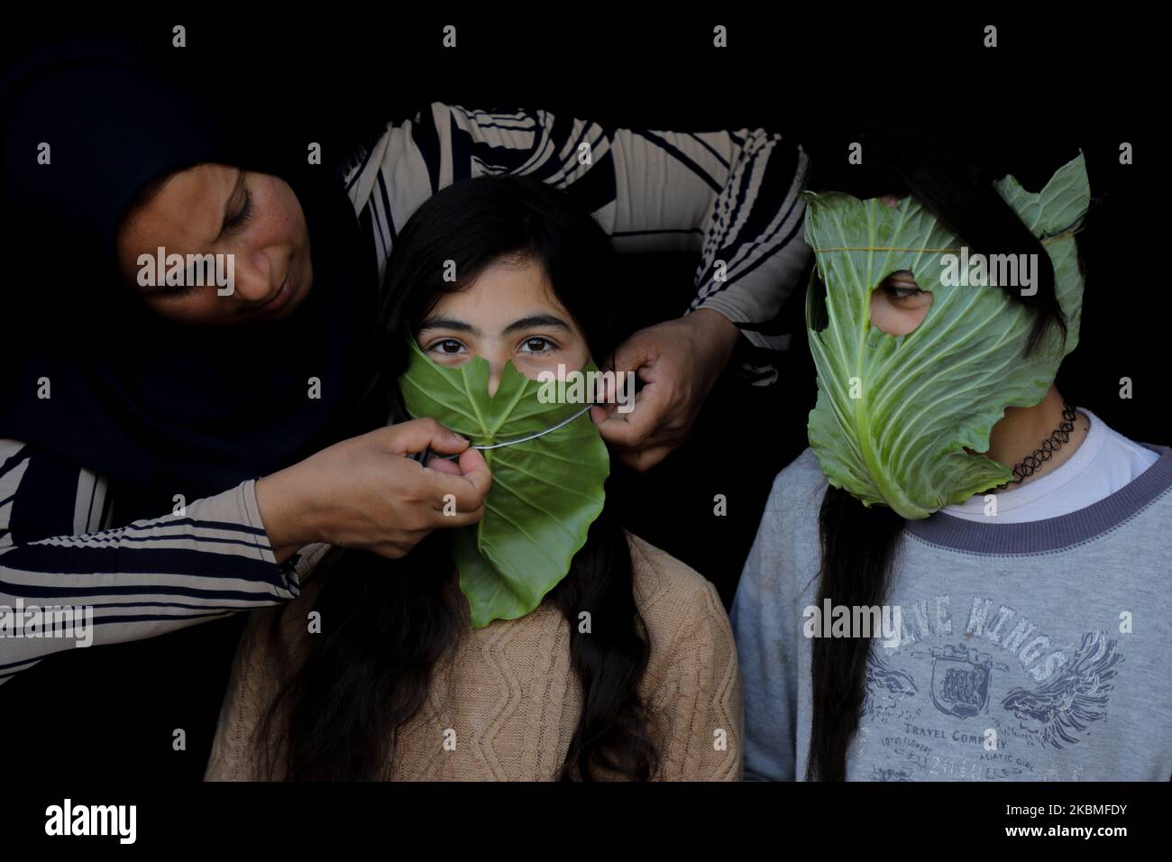 A Palestinian mother entertain her children with makeshift masks made ...