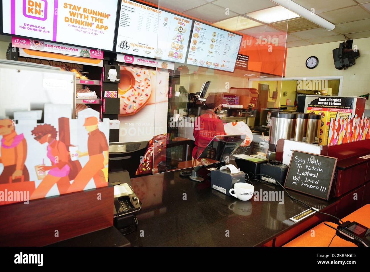 A view of a Dunkin' Donuts cashier protected by a plastic partition as ...