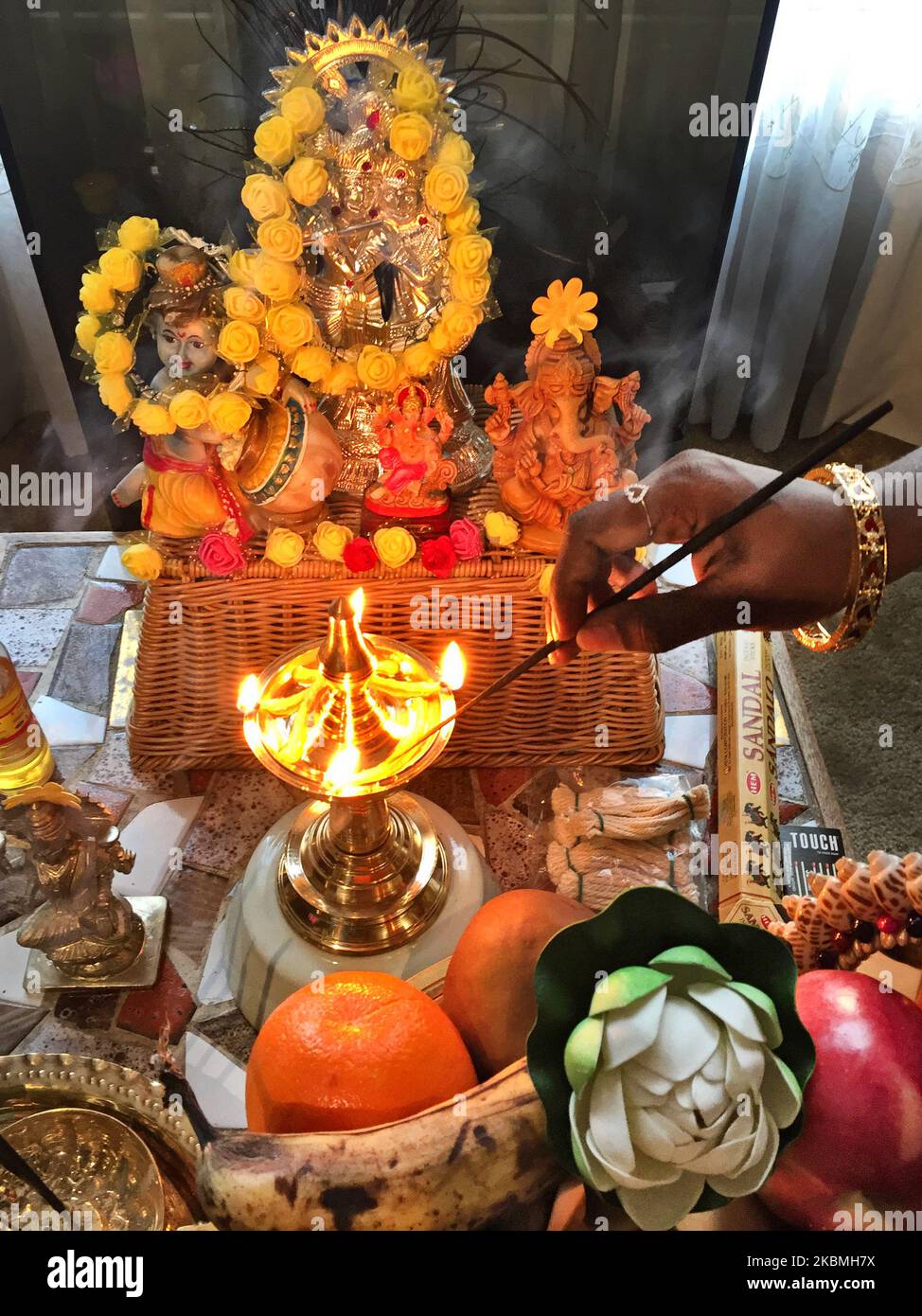 Woman lighting a lamp for a traditional Vishu kani (Vishukani) setting ...