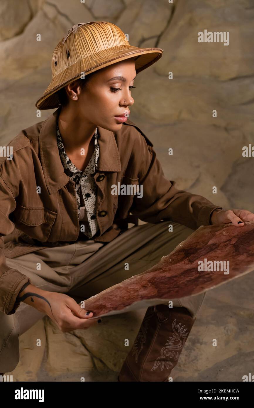 archaeologist in safari style outfit looking at ancient map while ...