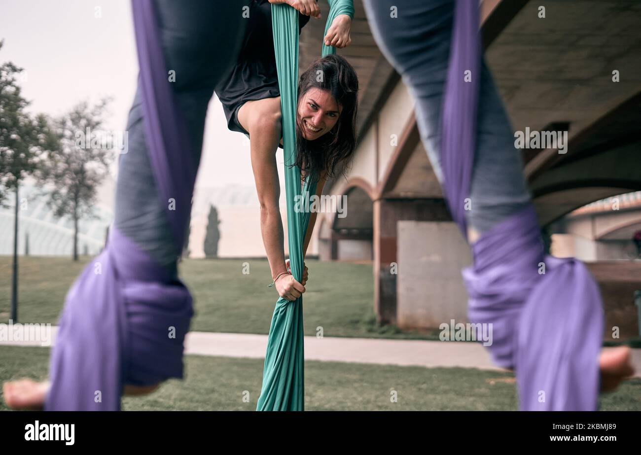Young caucasian woman teaching her friends how to do some aerial silks ...