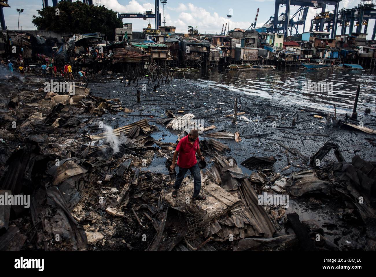 A man walks on the debris of his house destroyed after a fire broke out ...