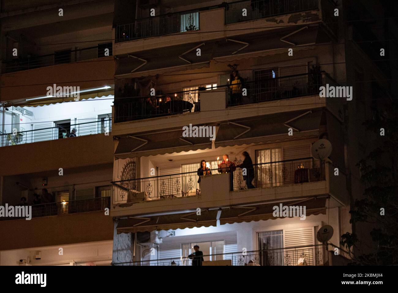 Believers in balconies in block of flats holding candles. Greek ...