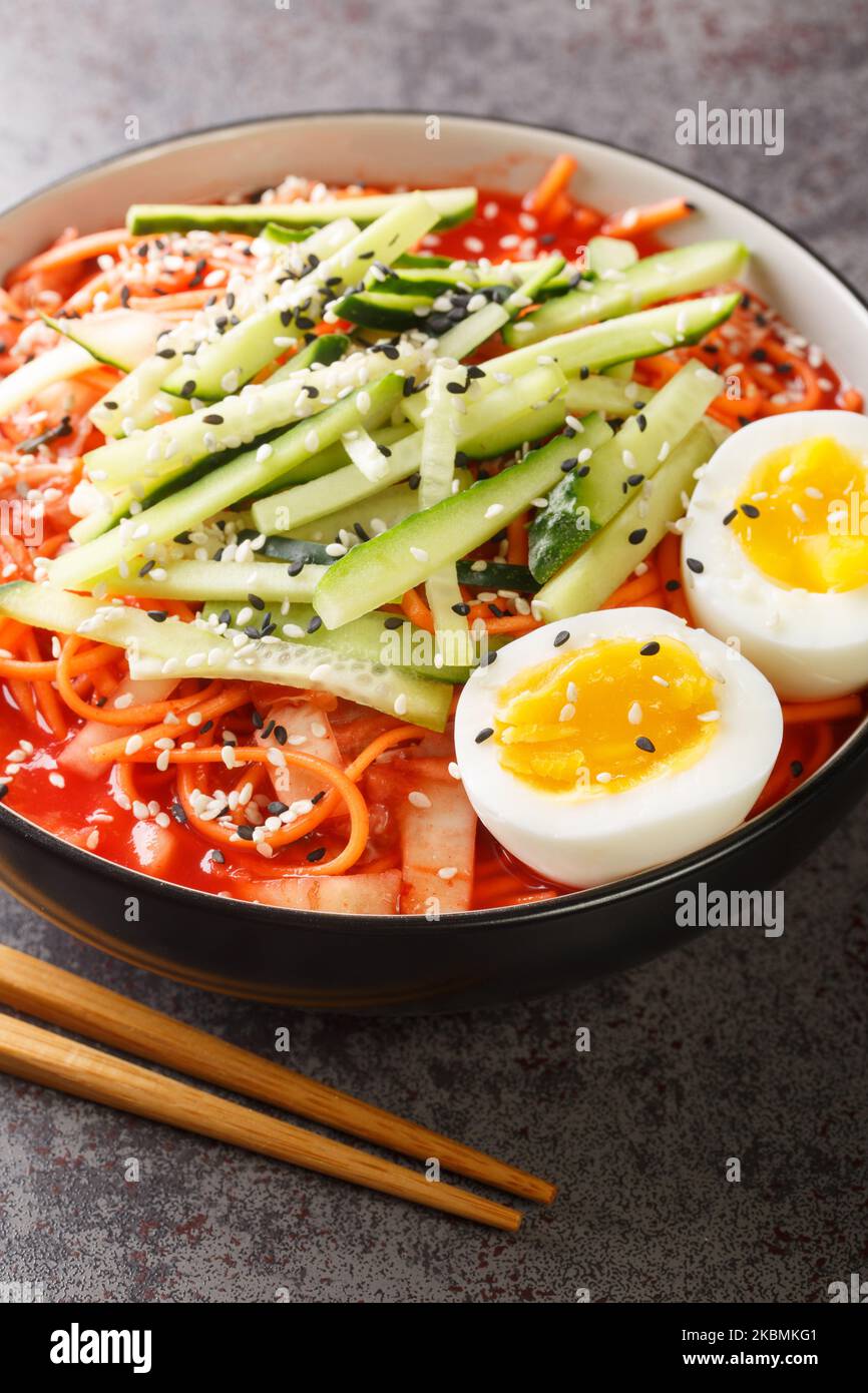 Korean cold noodle salad or bibim guksu, topped with boiled egg, sesame ...