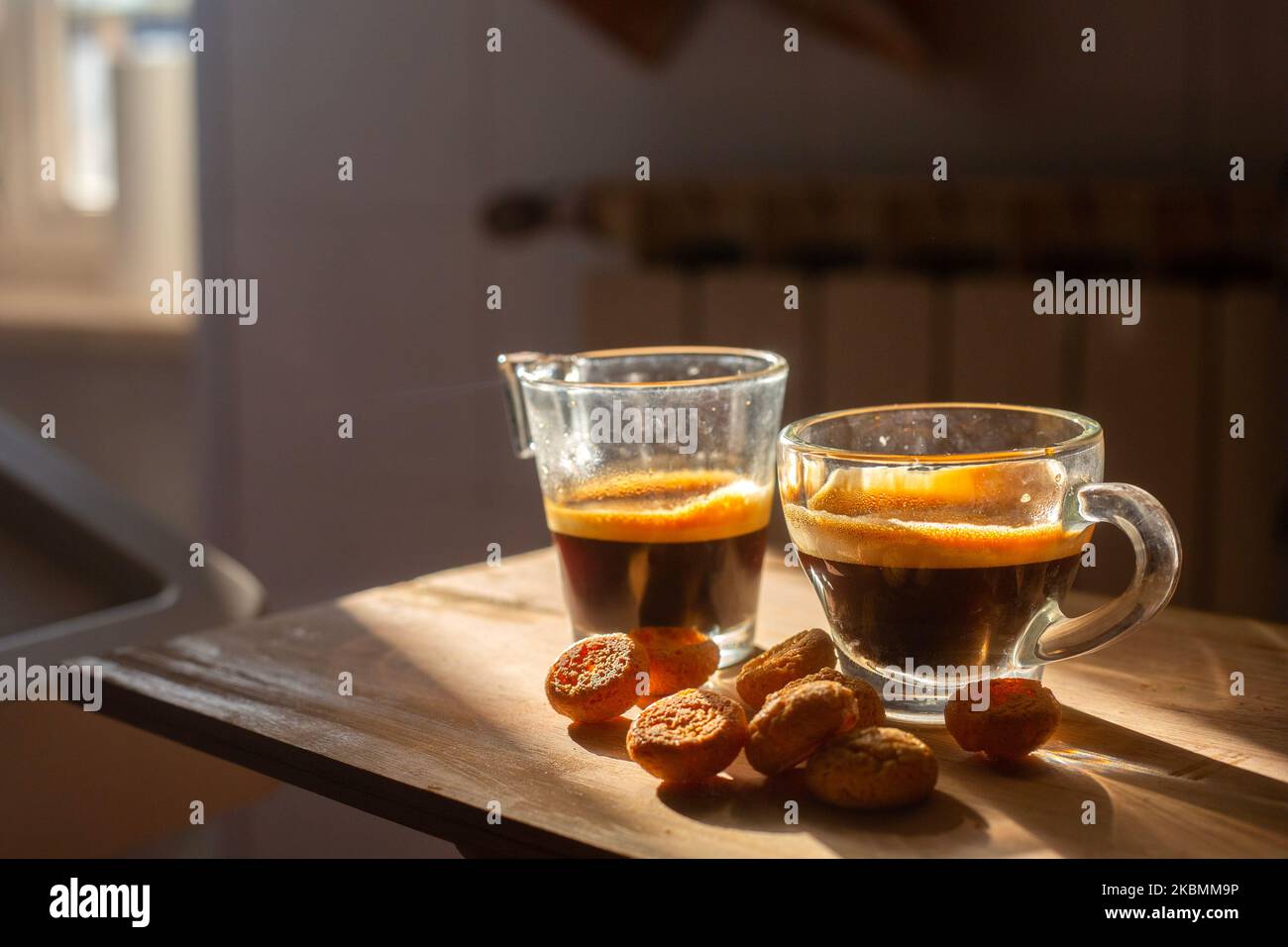 Two transparent cups of italian espresso on wooden surface with small ...