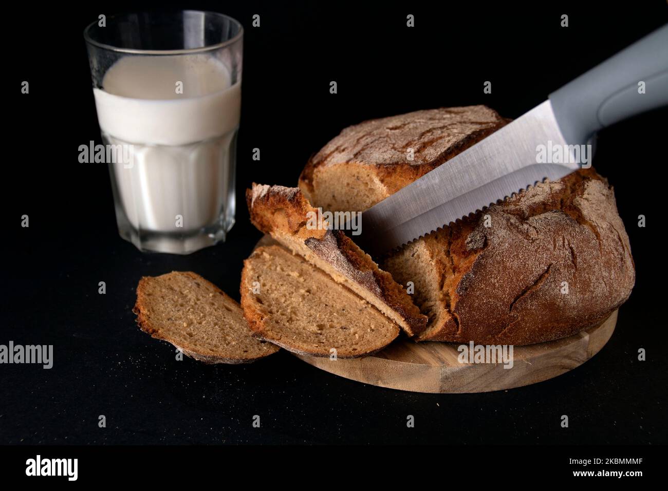 round sliced bread lying on a wooden board with a glass of milk next to ...