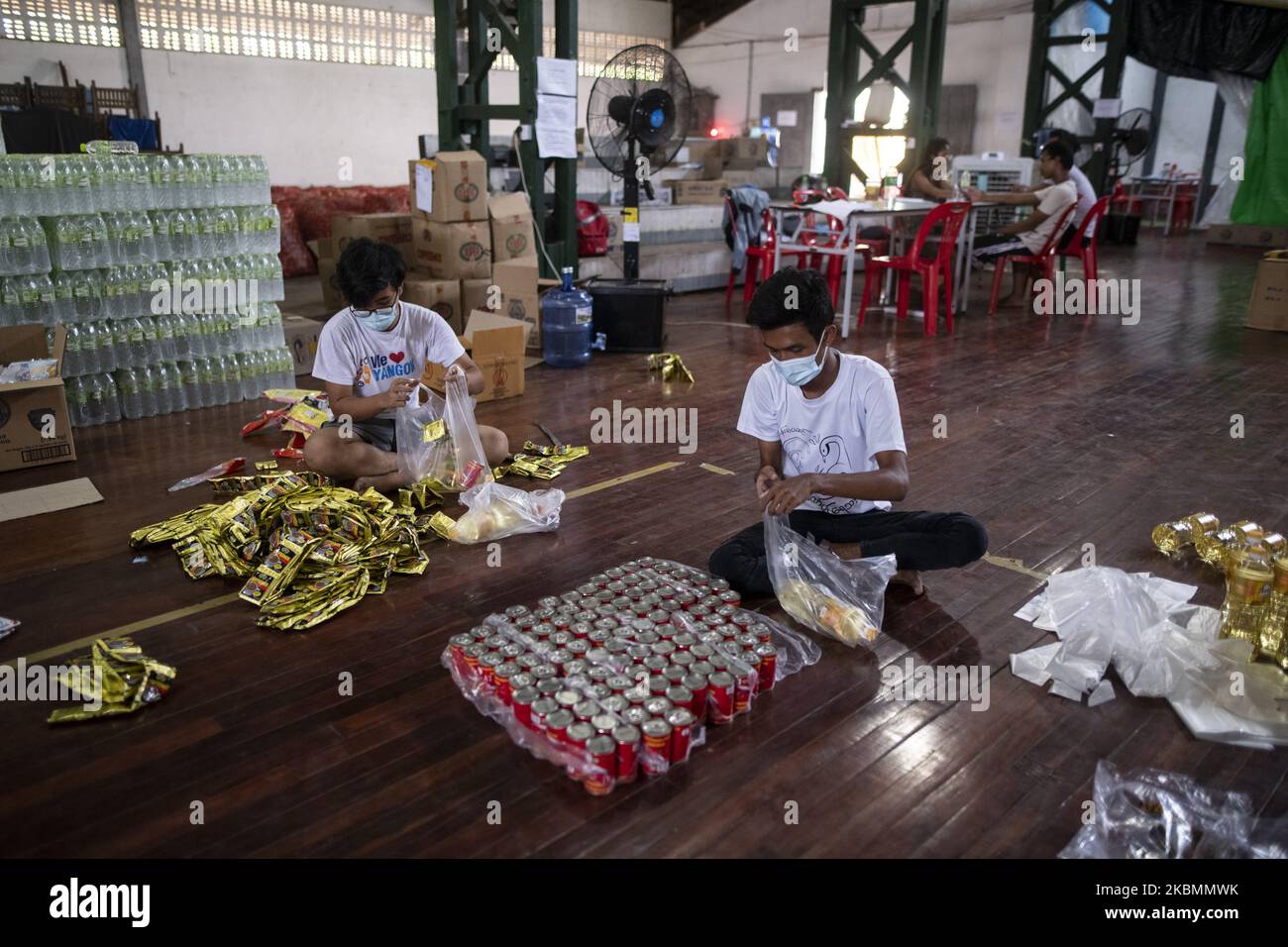 Volunteers prepare packages of dry rations of food and commodities ...