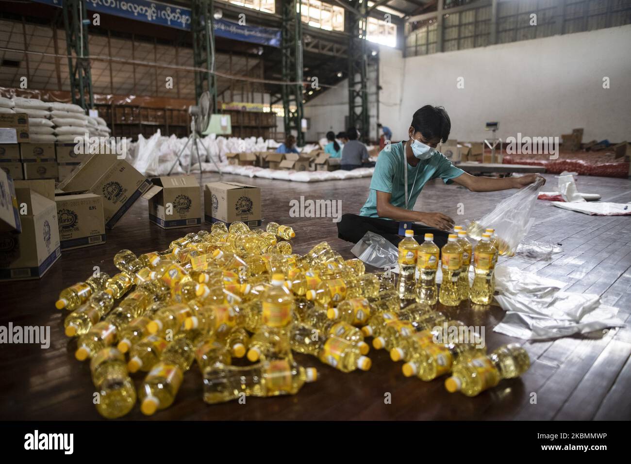 A volunteer prepares packages of dry rations of food and commodities ...