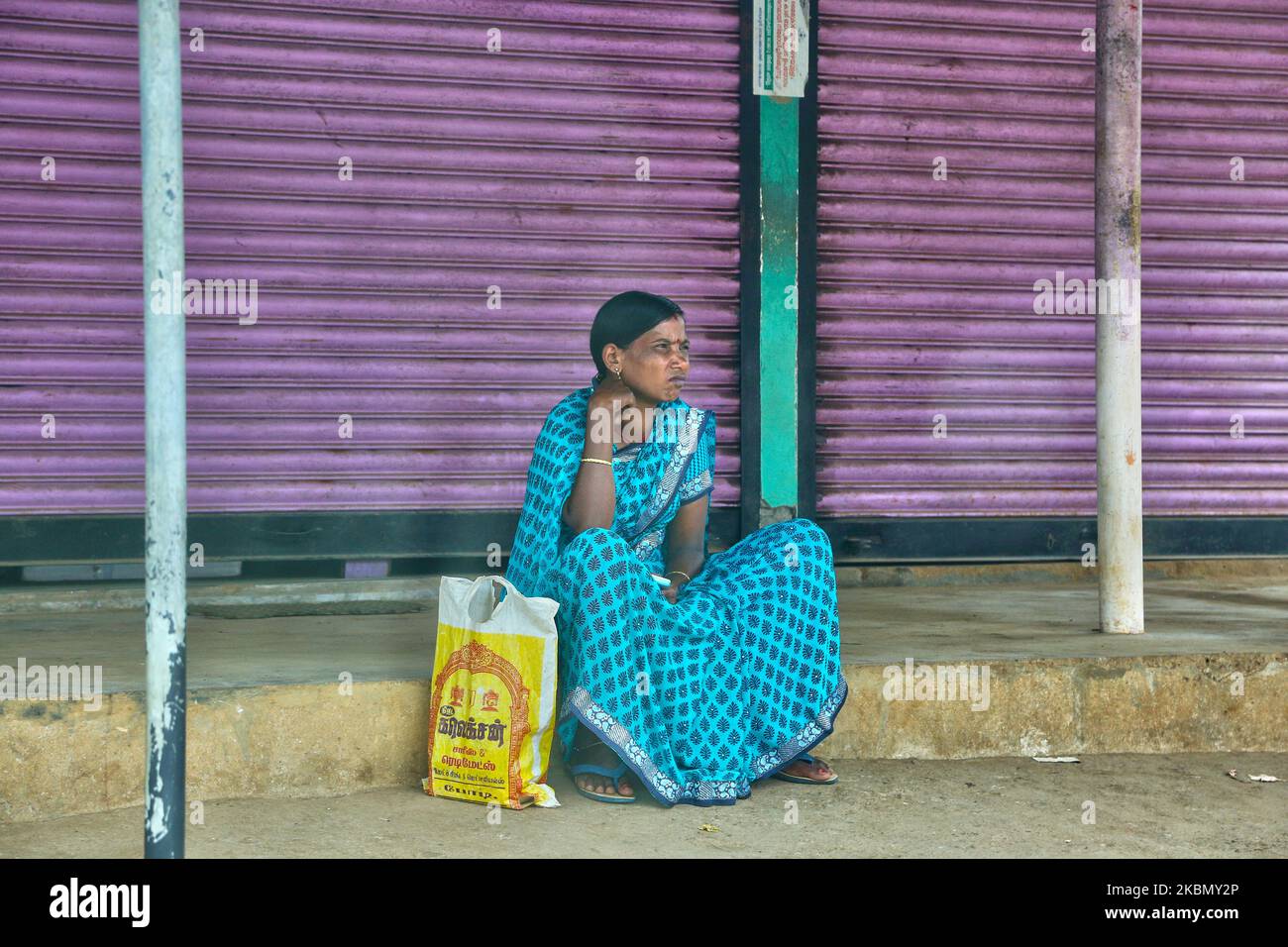 Tamil woman sits by a closed shop in the small village of Pooppara ...