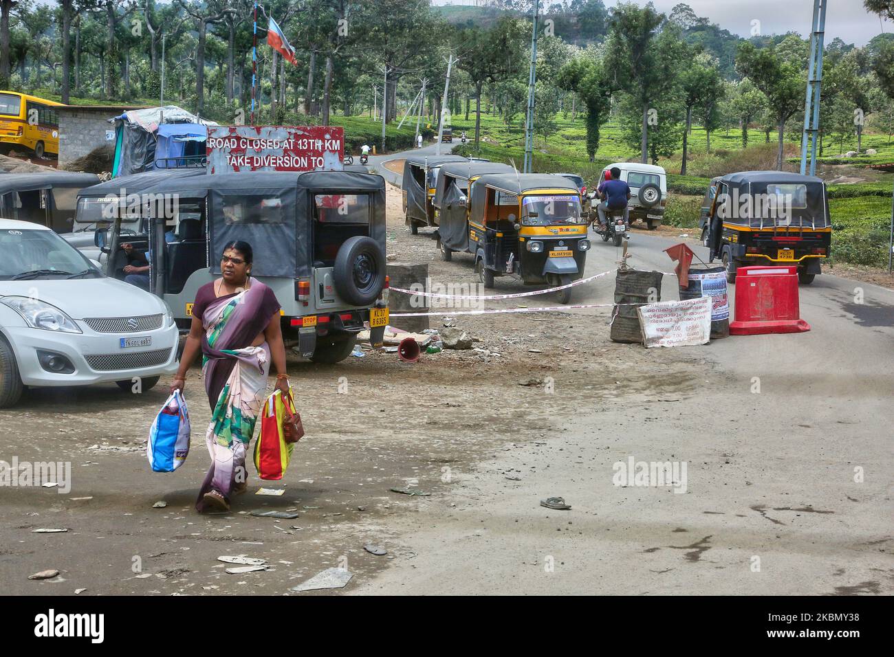 Tamil woman walks past a tourist taxi jeep stand in the small village ...