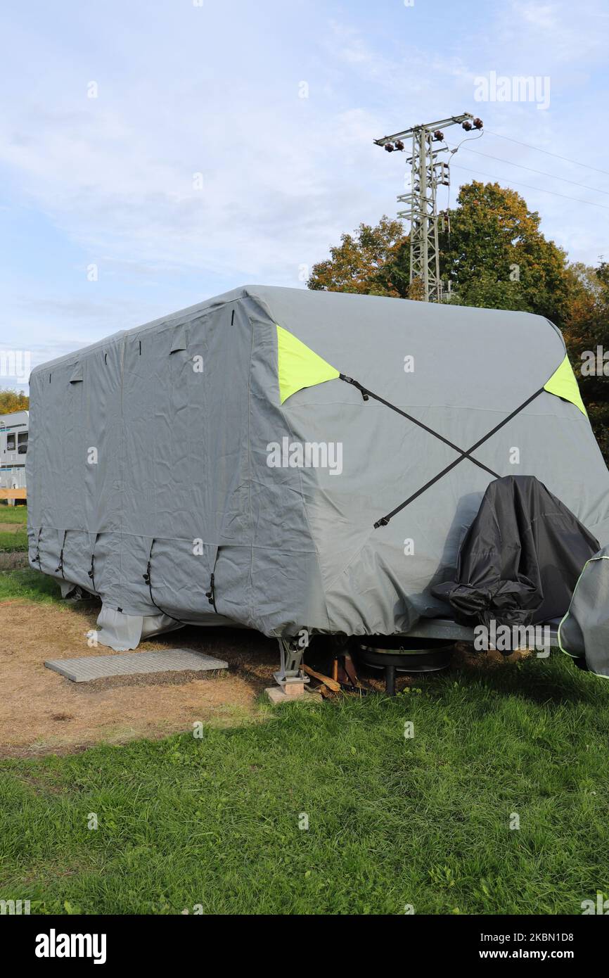 a caravan with a gray tarpaulin Stock Photo - Alamy