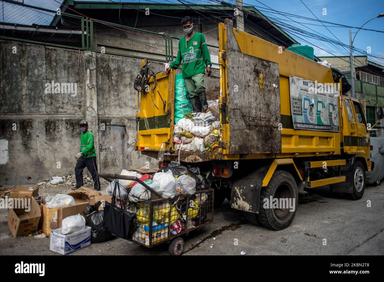 Garbage collectors load the dump trunk with household waste collected ...