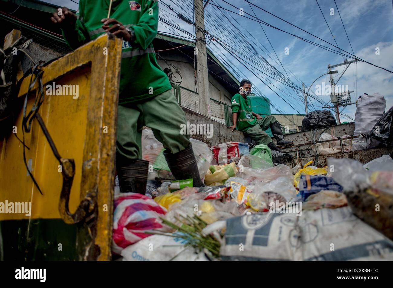 Garbage collectors load the dump trunk with household waste collected ...