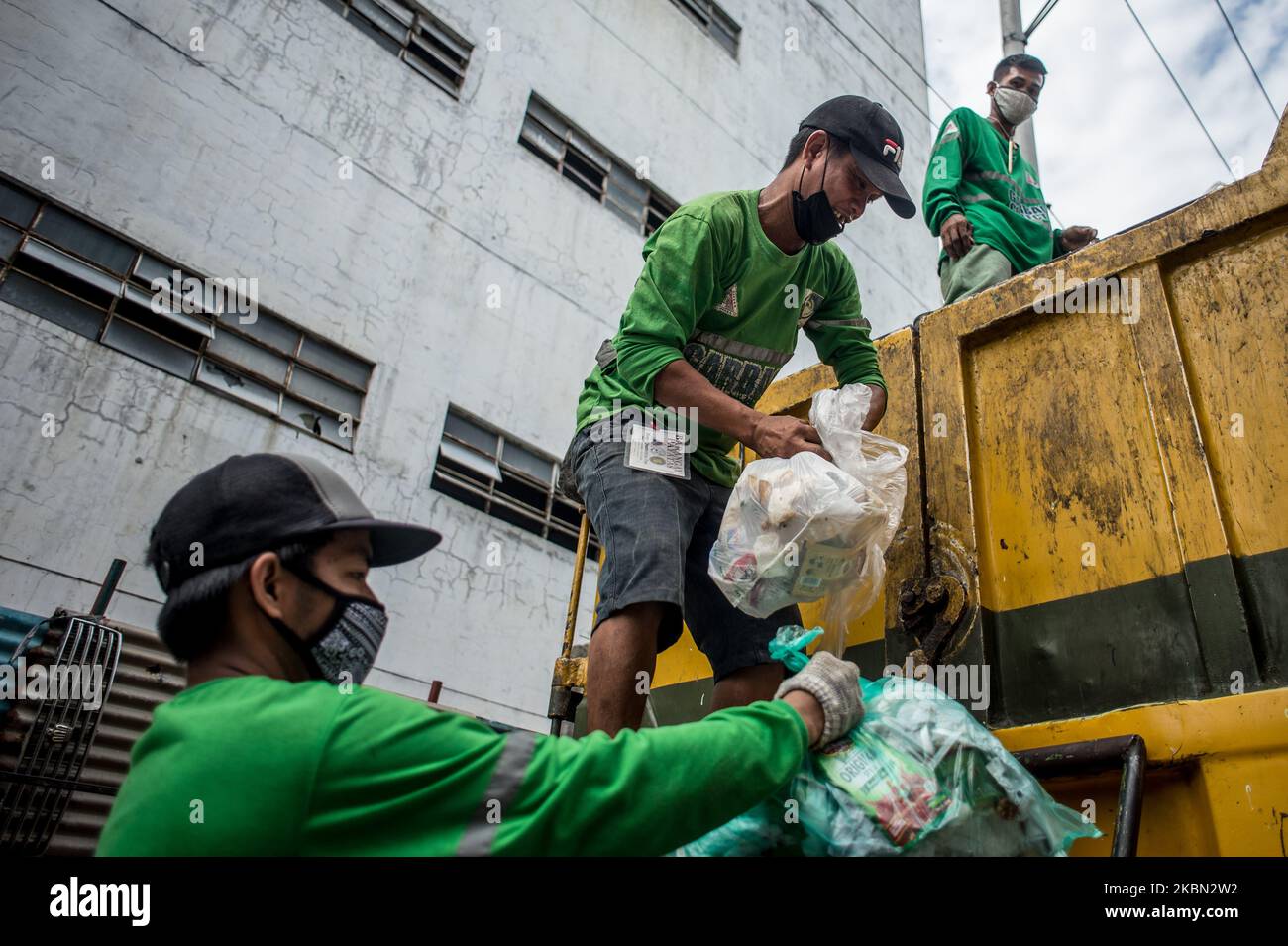 Garbage collectors load the drump truck with household waste from a ...