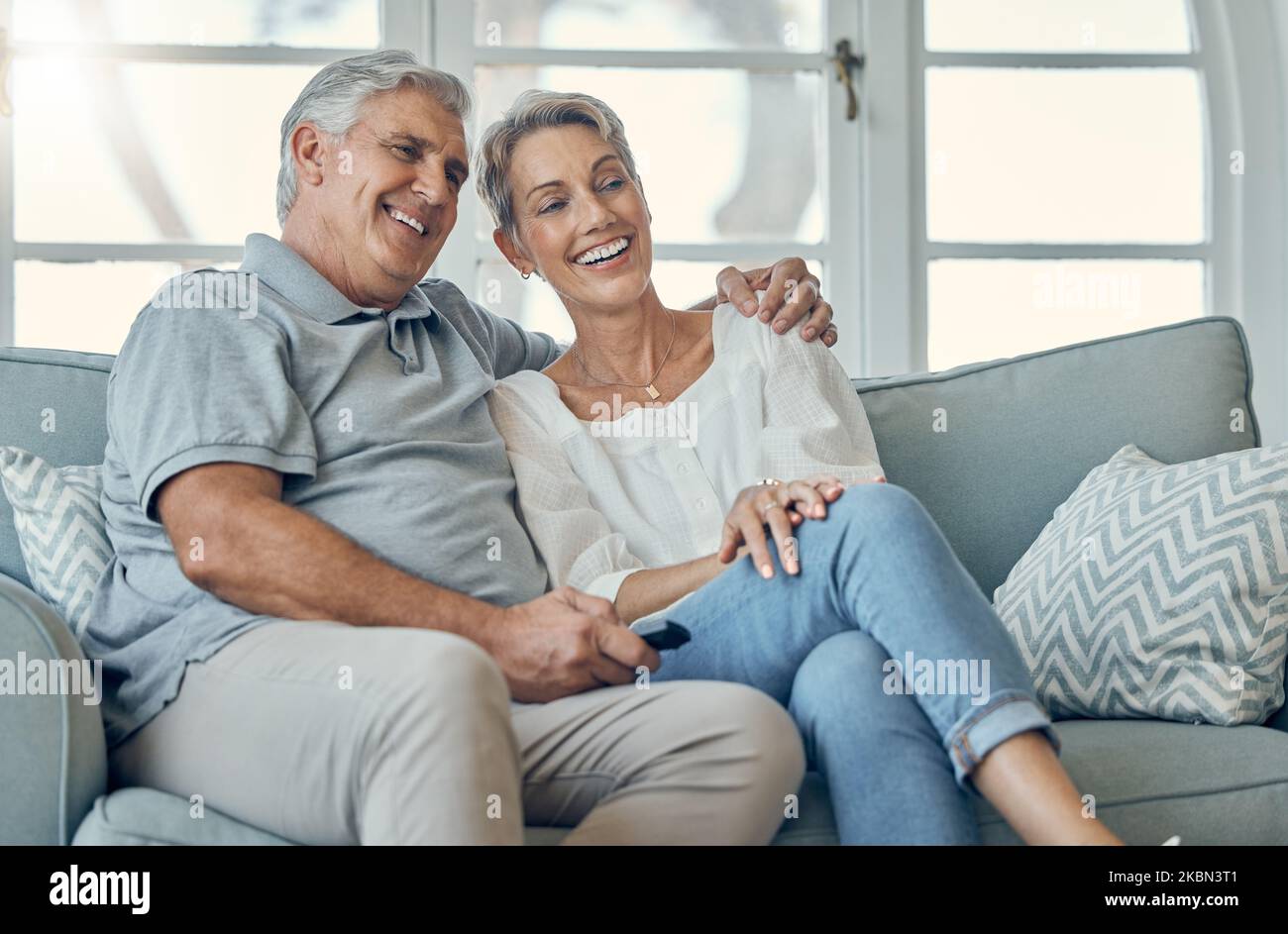 Happy senior couple, hug and watching TV for entertainment, relax or bonding time together at ...