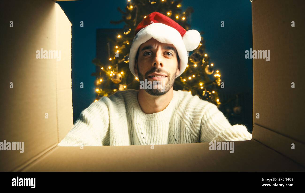 Happy guy looks inside a Christmas box Stock Photo - Alamy