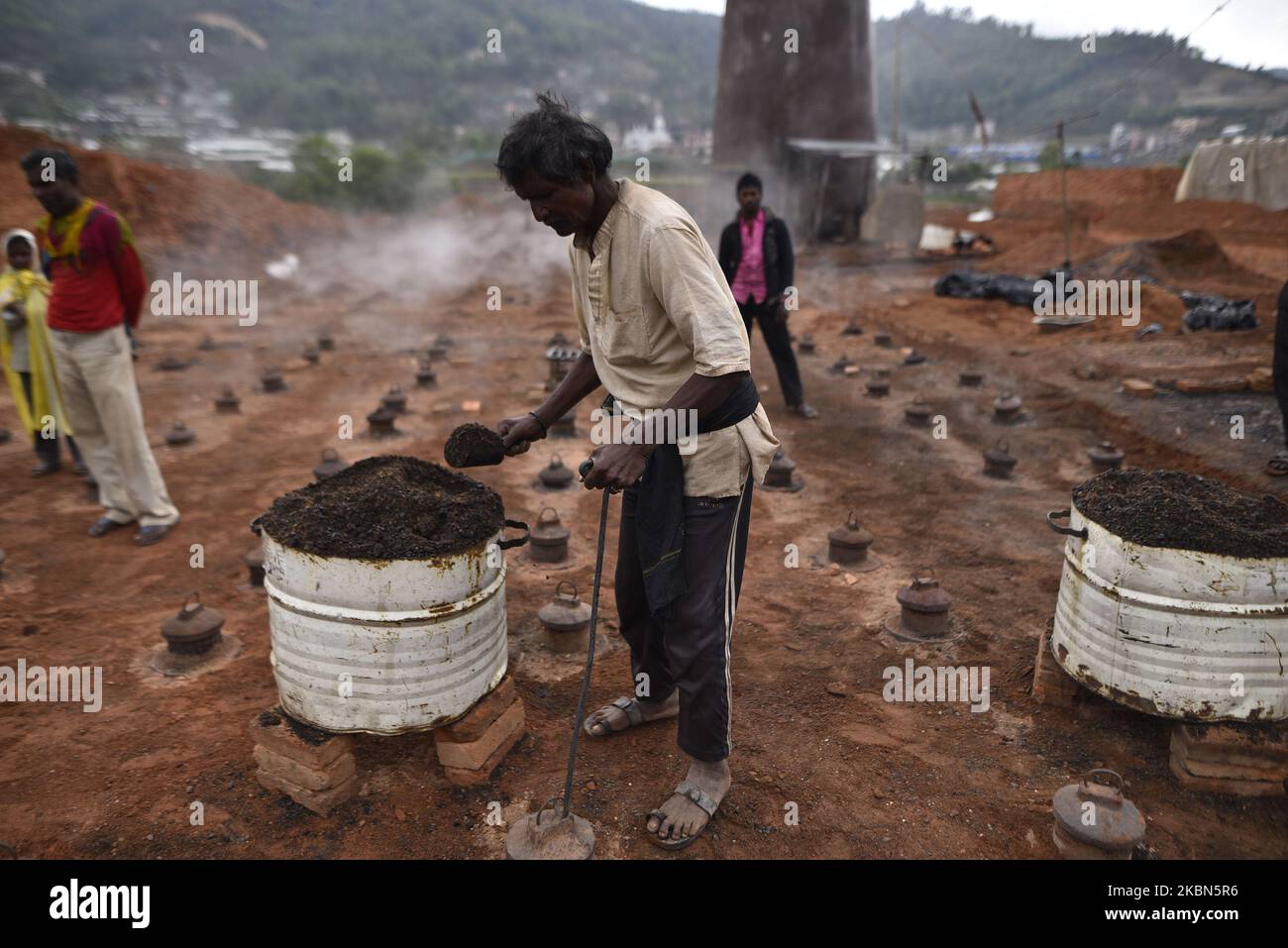 A Migrant Indian labourer add sawdust and coal in firing zone of fuel ...