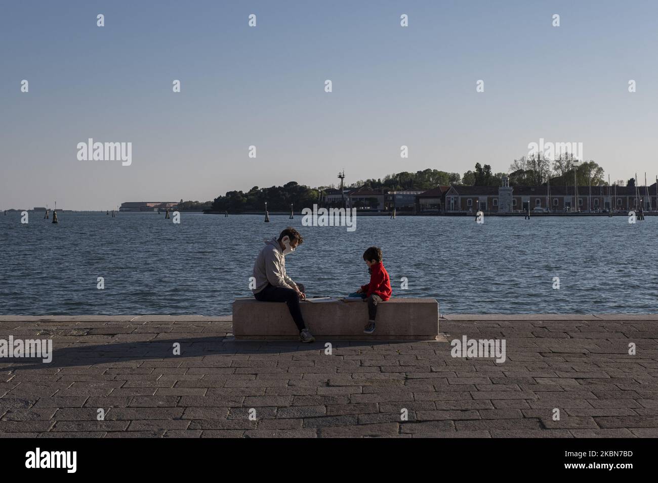 a dad with his son read a book sitting on a bench in Riva dei Sette ...